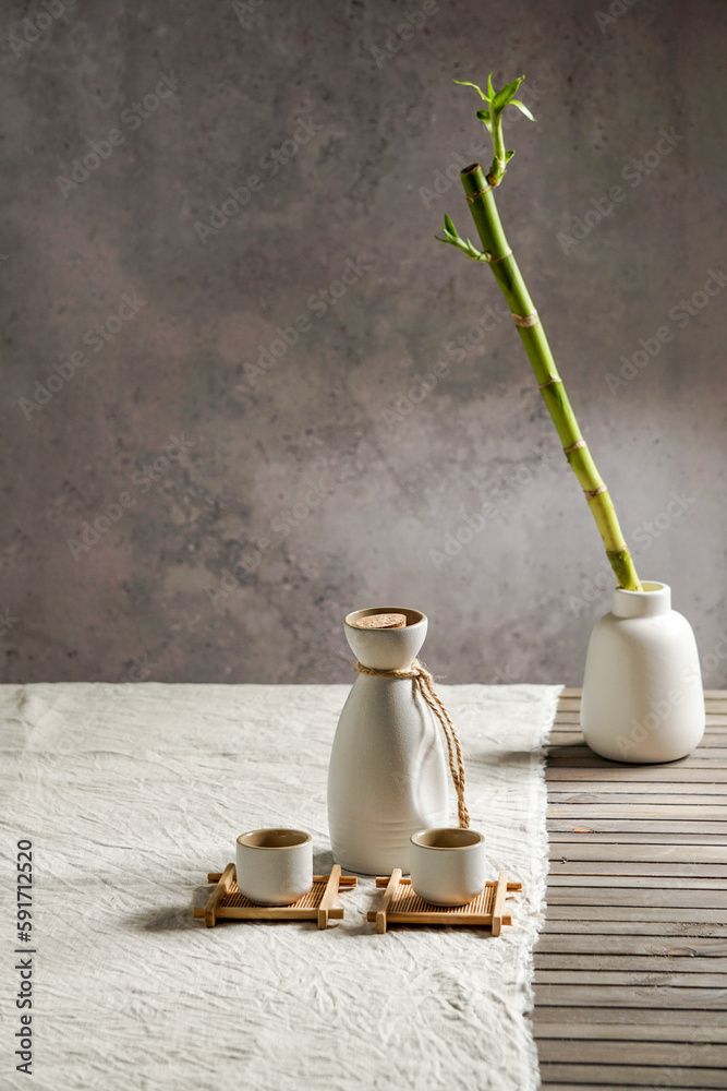 Japanese sake still life with a sprig of bamboo, light linen background ...