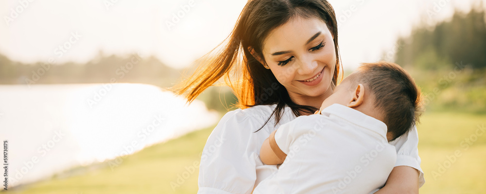 An intimate portrait of mother holding her sleeping baby in park at ...