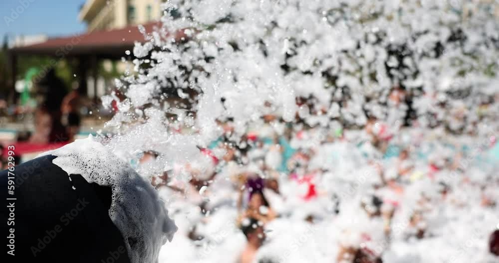 Fresh white foam sprayed from air gun falling on happy people having ...