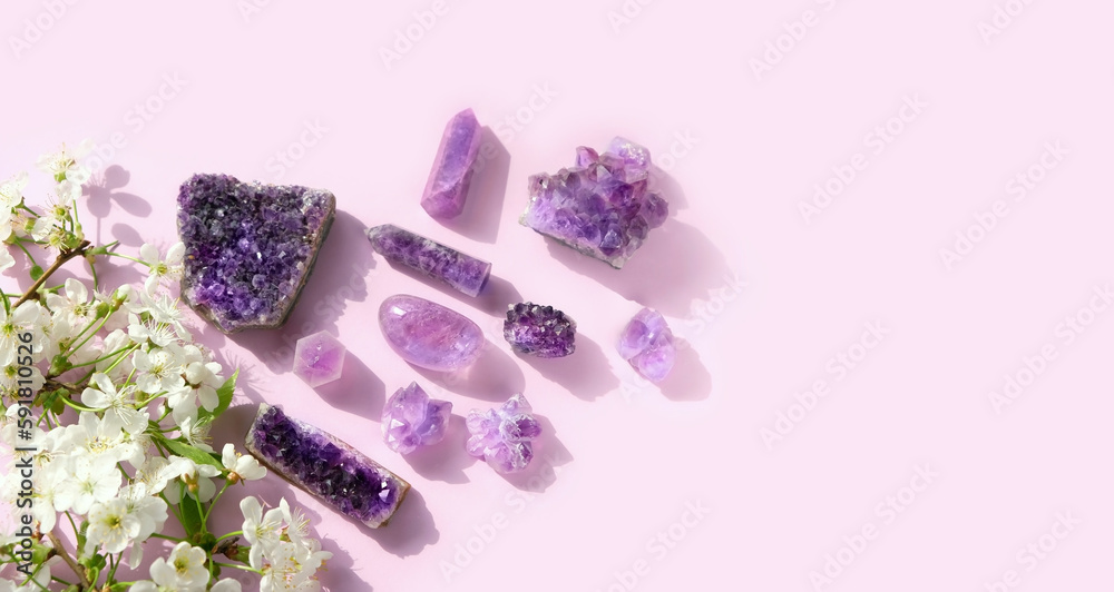 amethyst minerals set and white flowers close up on abstract light pink ...