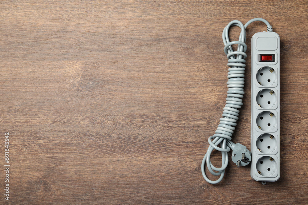 Power strip with extension cord on wooden floor, top view. Space for ...