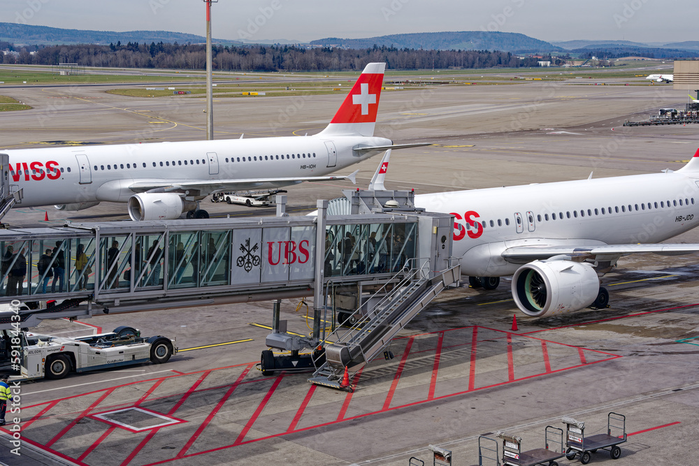 Passengers boarding Swiss airplane by passenger boarding bridge at ...