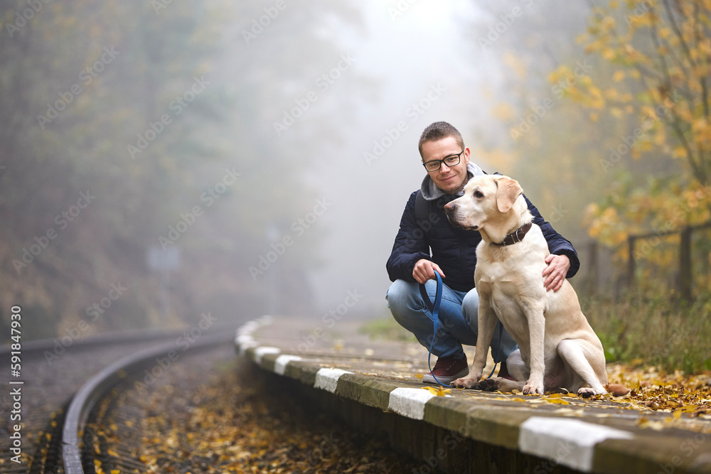Man with dog on leash are waiting on platform of railway station. Pet ...