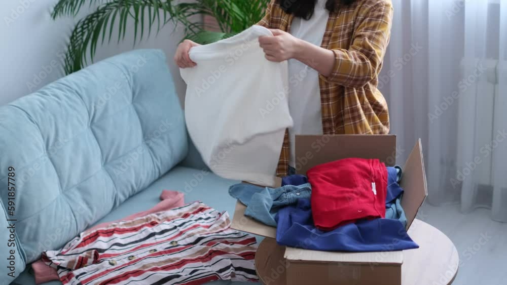 woman sorting through a clothing, photographing each piece with her ...