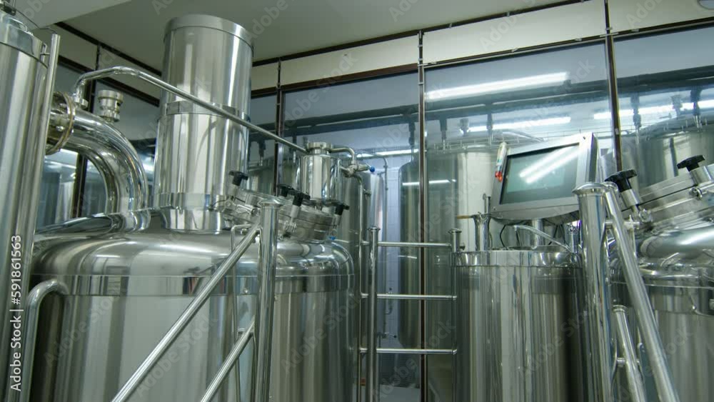 Arc shot of shiny stainless steel brewhouse with large mash tun, lauter ...