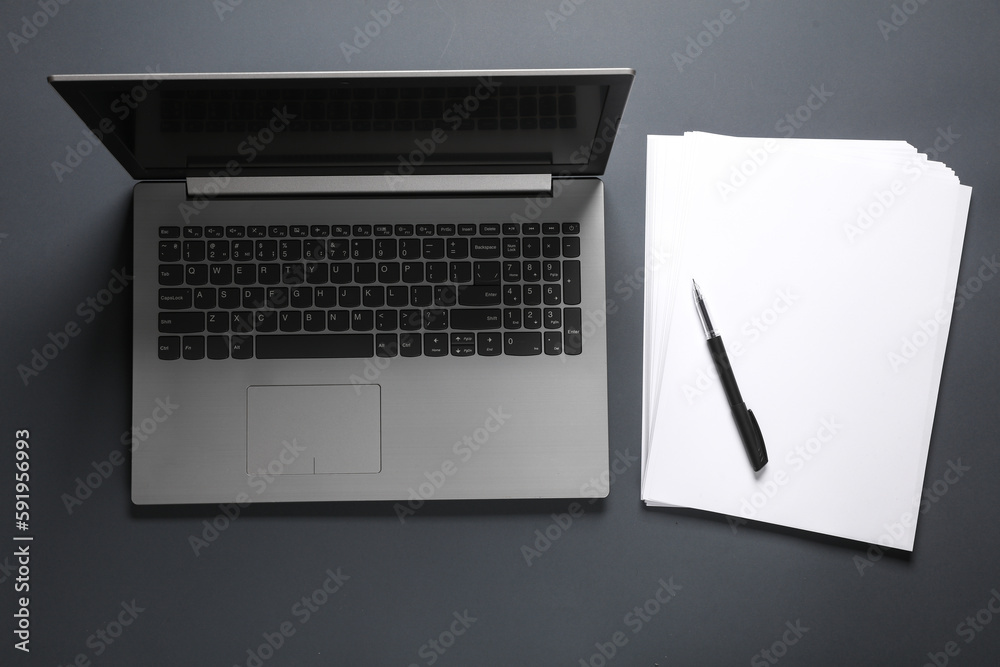 Laptop and white a4 paper with a pen on a dark background. Business ...