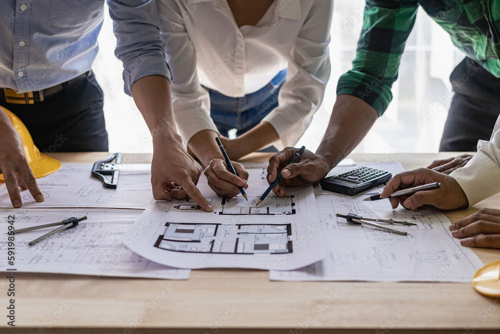 Engineer pointing at blueprint and using laptop to draw project design ...