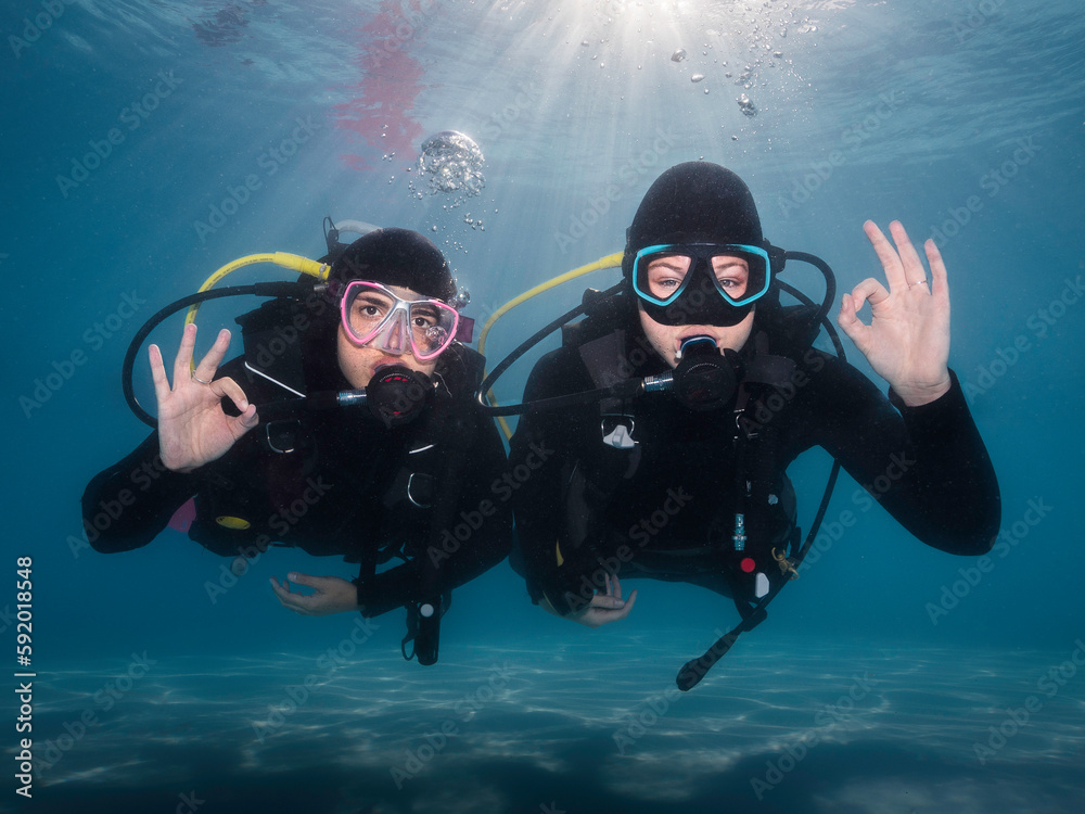 Closeup of two happy scuba divers underwater facing the camera showing ...