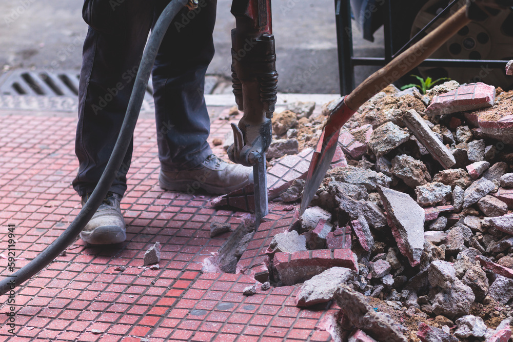 Process of sidewalk road repairing with jackhammer, builder worker with ...