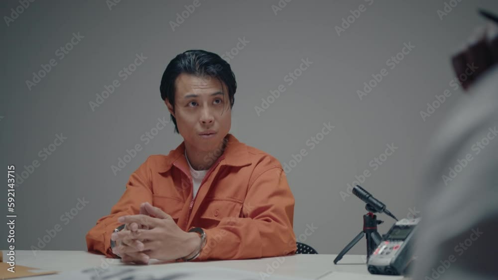 Arrested Asian male villain in orange jumpsuit and handcuffs sitting ...