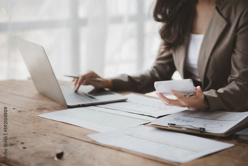 Businessman using a calculator to calculate numbers on a company's ...