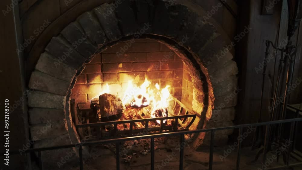close-up of a small circular brick fireplace with a cozy fire burning ...