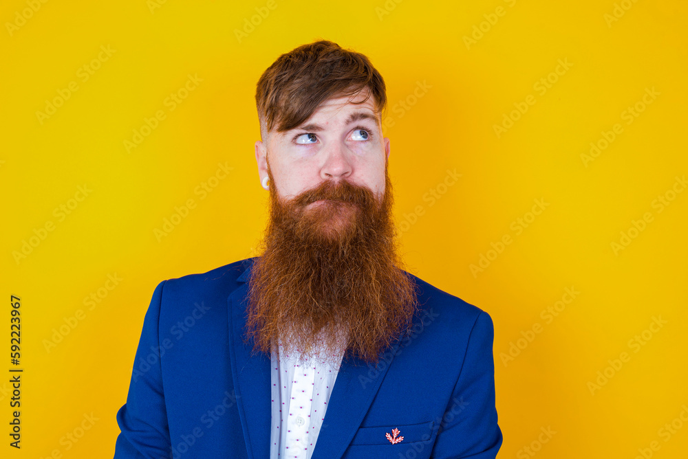 red haired man wearing blue suit over yellow studio background making ...