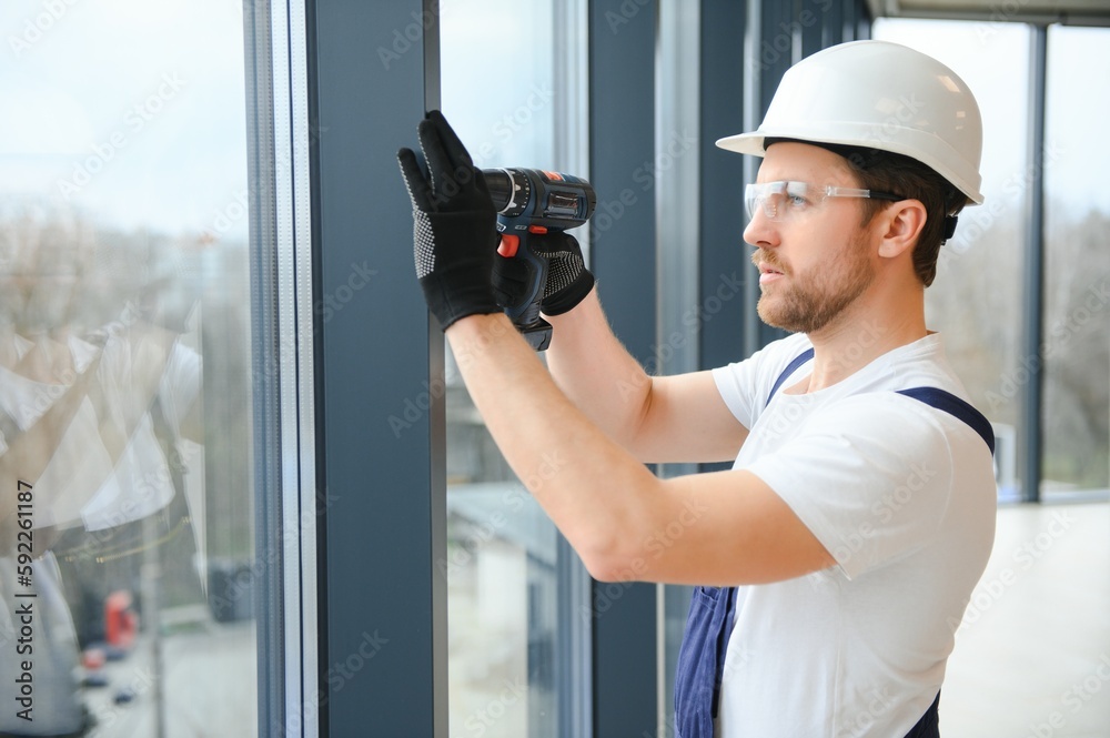 handsome young man installing bay window in new house construction site ...