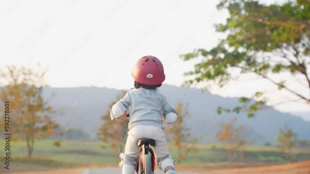 Behind shot of young playful child riding standing bike on the natural ...