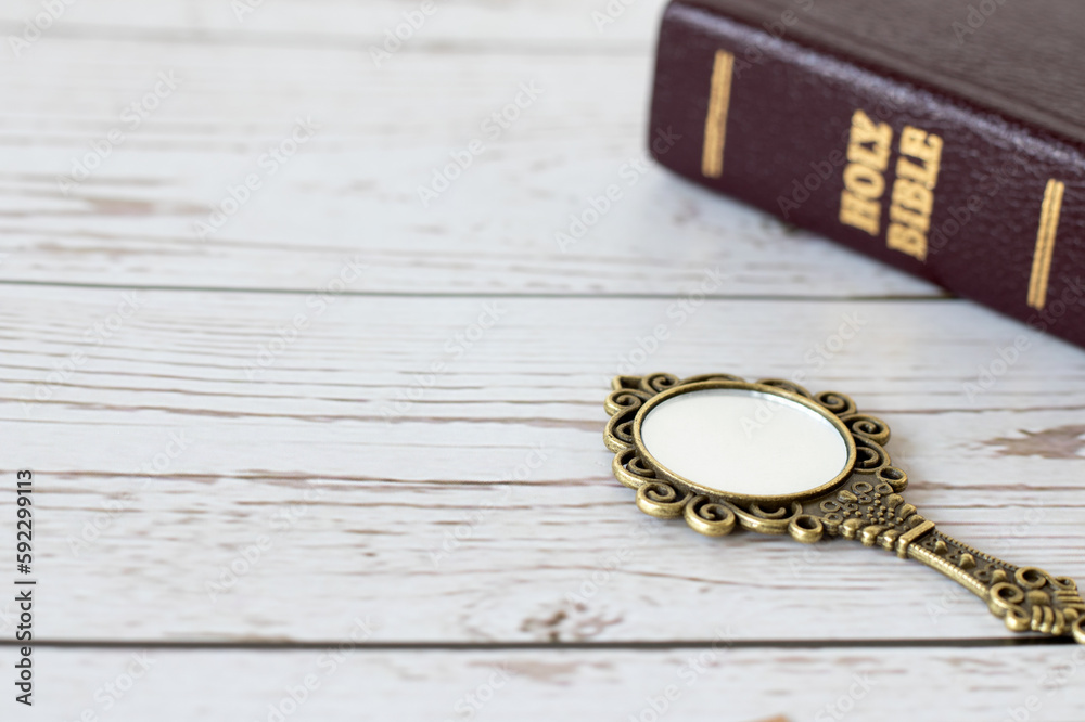 Ancient golden mirror and closed holy bible book on wooden table ...