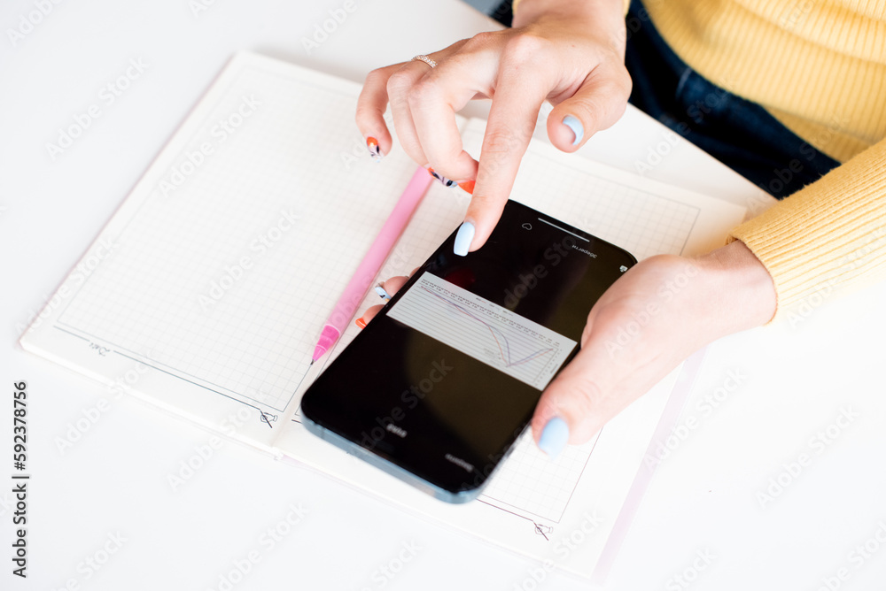 Close-up hands of women pressing smartphone looking business charts ...