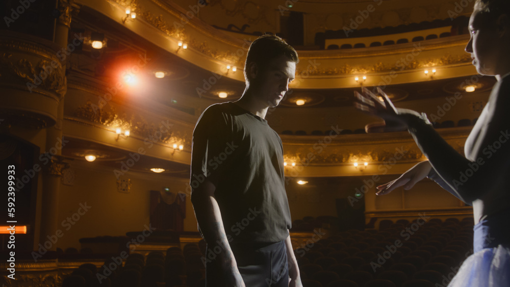 Ballerina with partner stands on theater stage and discusses preparing ...