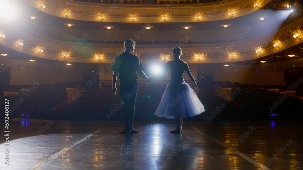 Pair of ballet dancers bow down in front of rows of seats. Ballerina ...