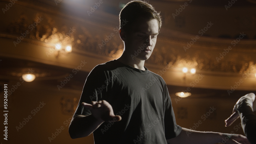Concentrated ballet male dancer stands with ballerina on theater stage ...