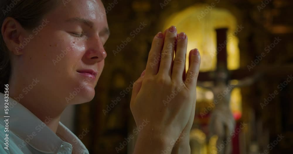 Young woman at prayer service prays in shrine of the Lord. Crucified ...