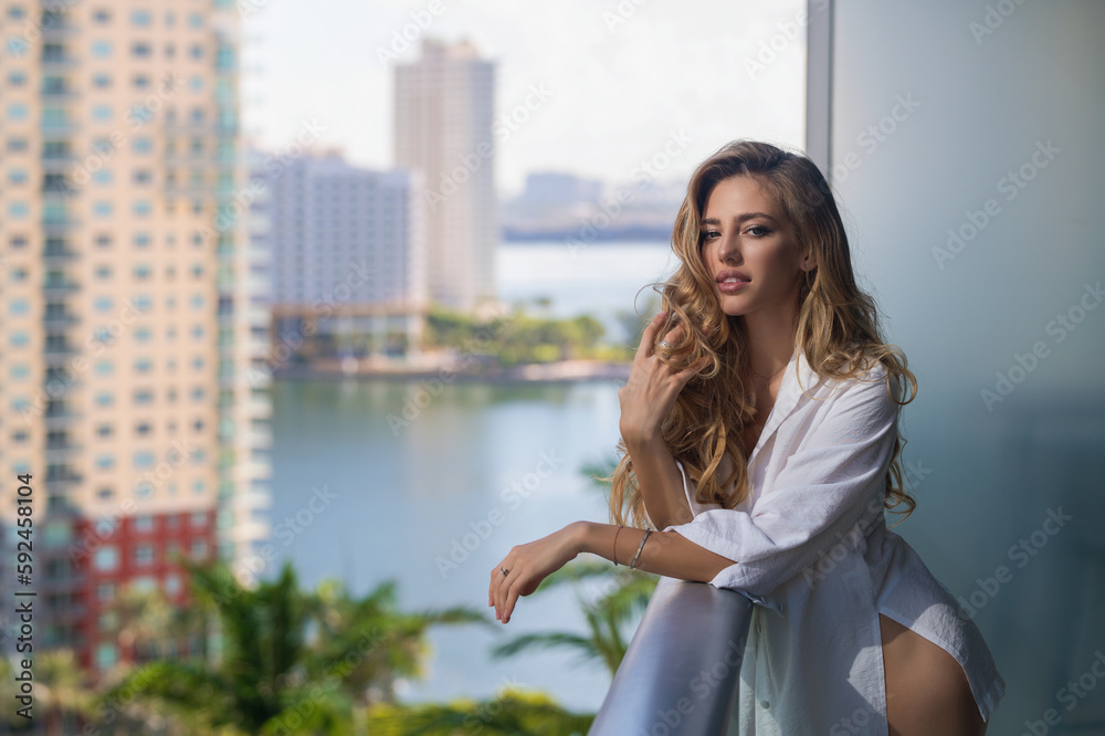 Woman on the balcony enjoying city view. Attractive girl with long ...