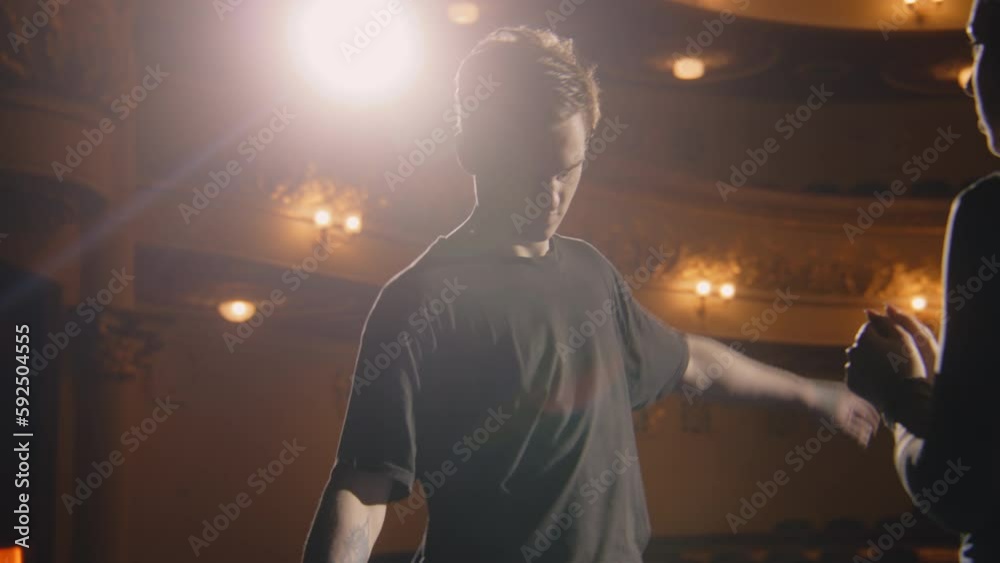 Concentrated ballet male dancer stands with ballerina on theater stage ...