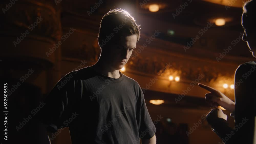 Concentrated ballet male dancer stands with ballerina on theater stage ...