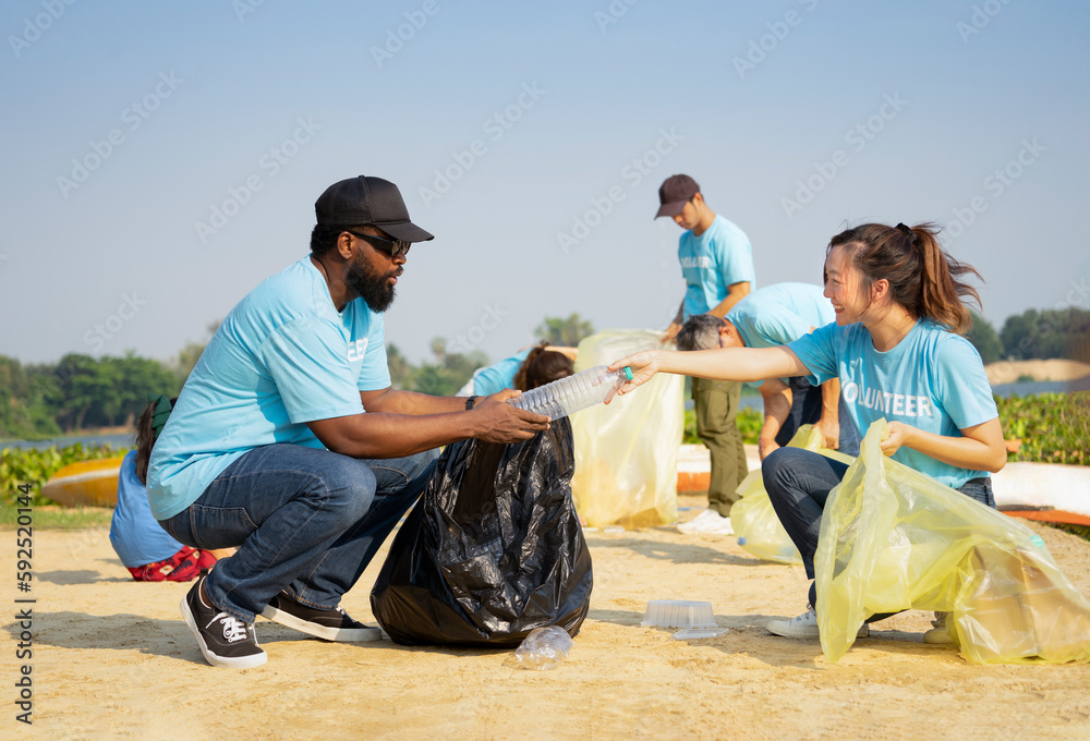 A diverse group of volunteers join together to cleanup the sand beach ...