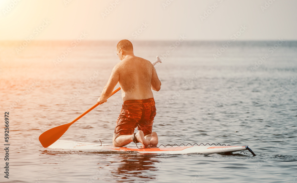 Active mature male paddler with his paddleboard and paddle on a sea at ...