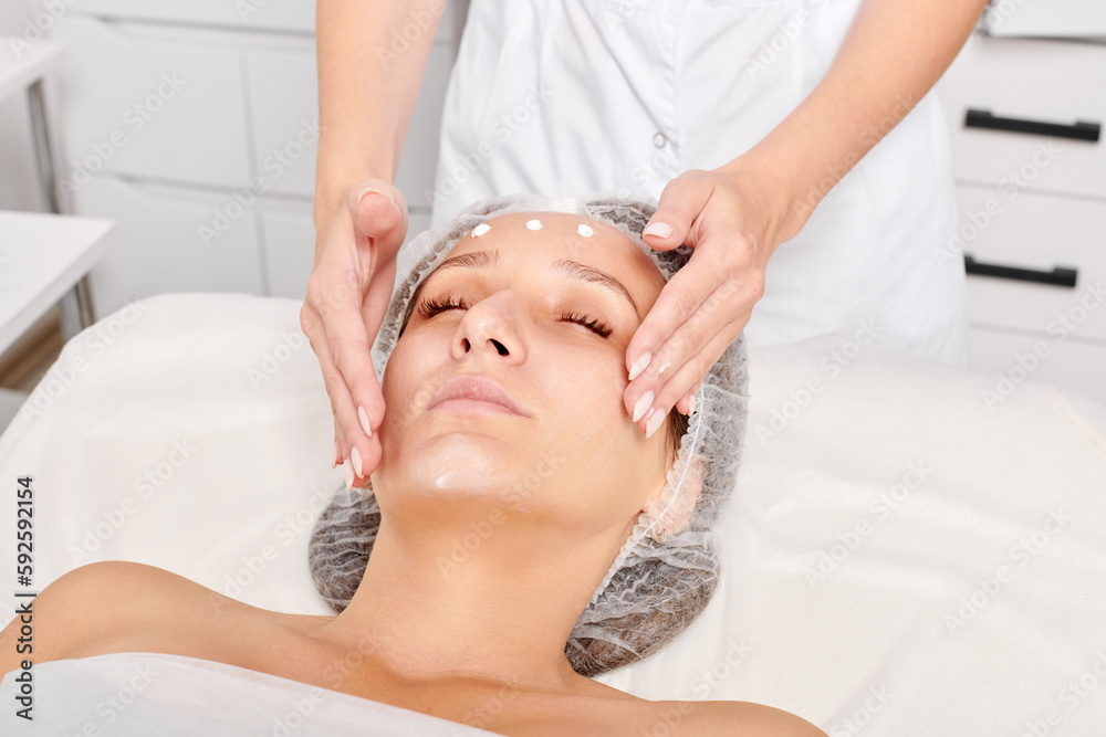 Beautician rubbing moisturizing cream mask into woman face skin for ...