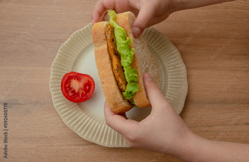 child's hand holding toasted chicken and lettuce sandwich bread between ...