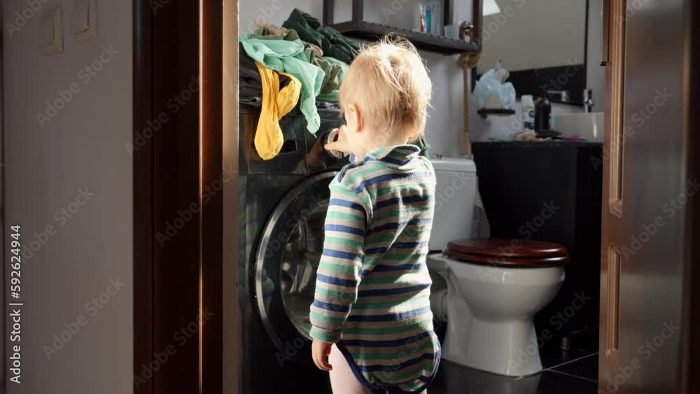 Little baby boy pressing knobs and buttons on working washing machine ...