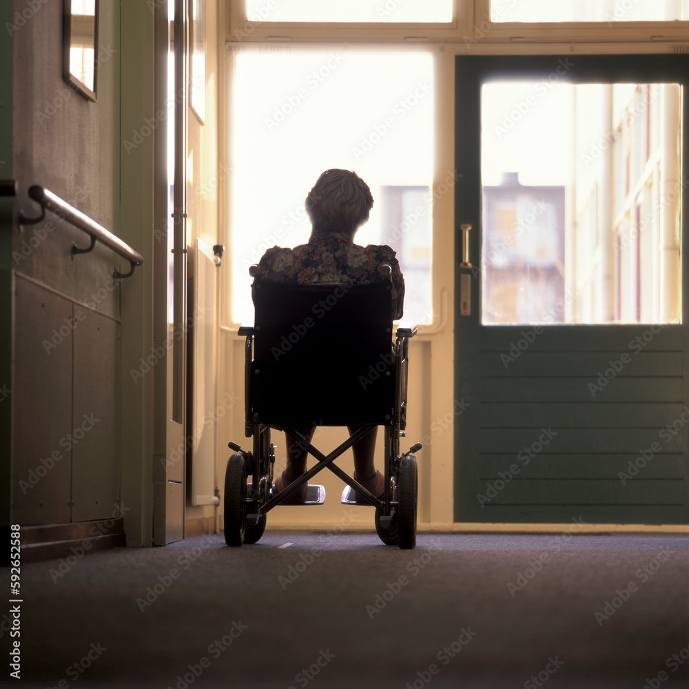 Back view of a female senior in a wheelchair in a nursing home looking ...