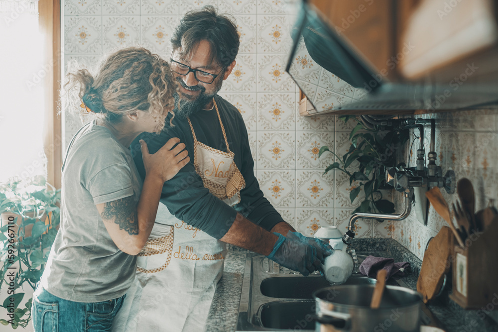 One man helping wife in housework job washing the dishes in the kitchen ...
