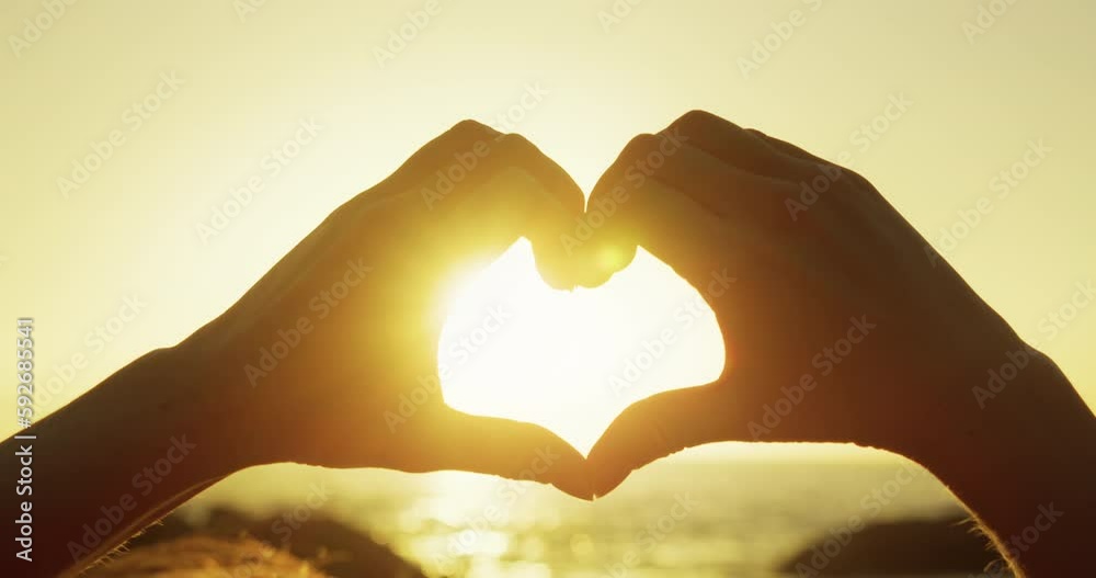 Video Stock Woman catching setting sun with heart shaped fingers. Young ...