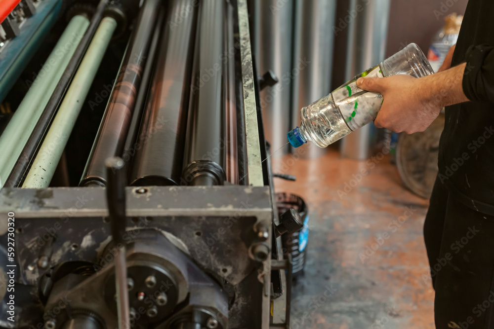 An artist cleaning a lithographic press or rolling press used for ...