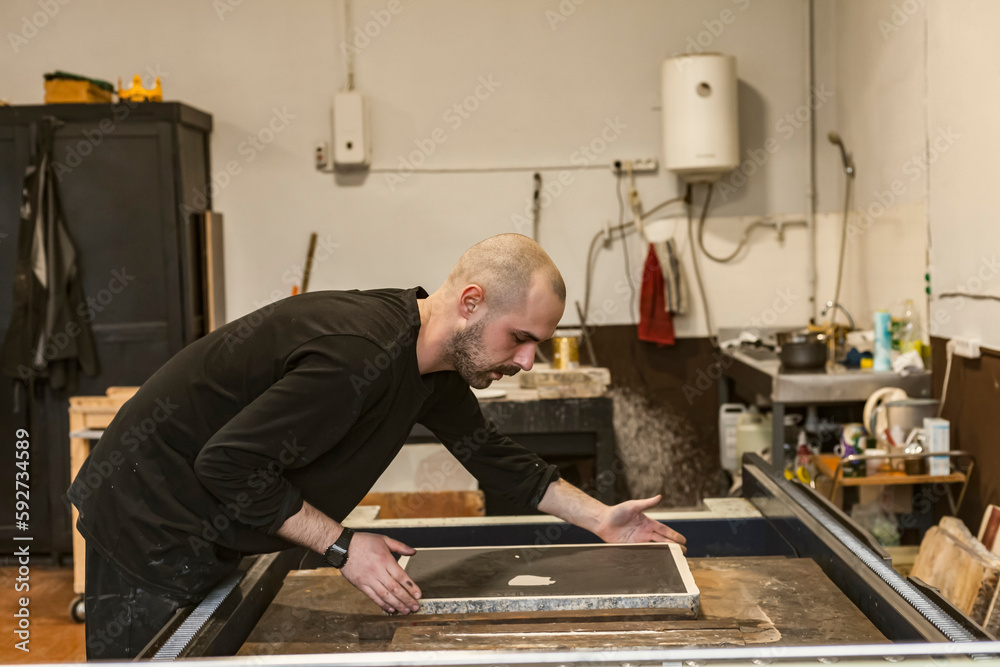 The artist placing a Lithographic limestone on a lithographic press or ...