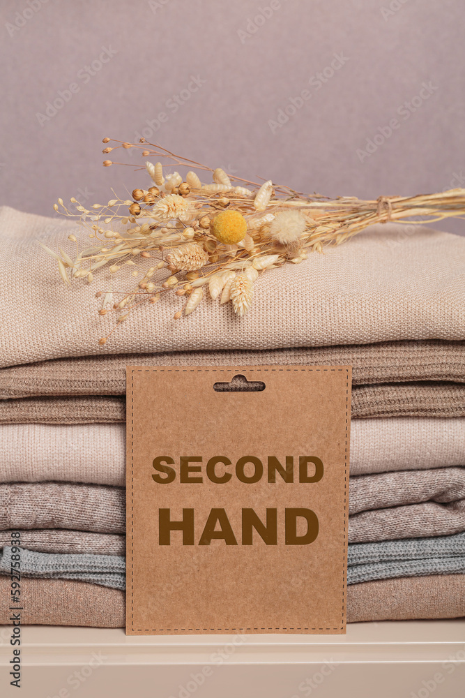 Stack of clothes with used wardrobe and card with inscription Second ...