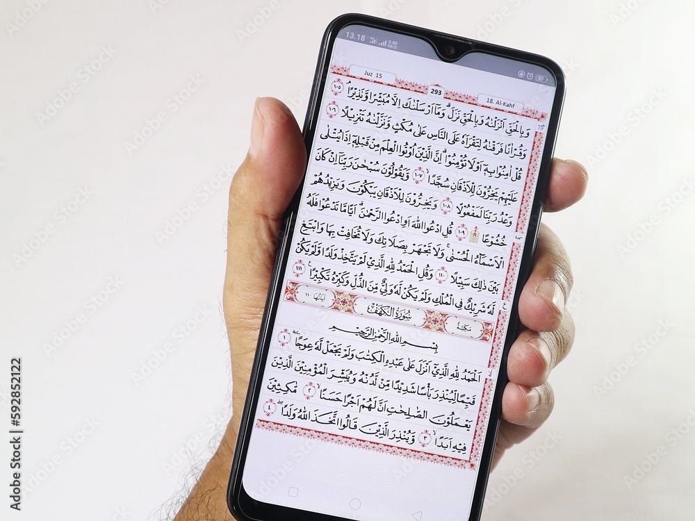 Hand holding mobile phone showing Quran application at surah al Kahfi ...
