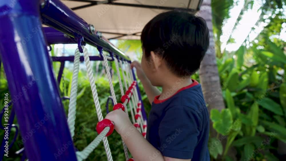 4K, Asian male child, is standing facing high rope net, in order catch ...