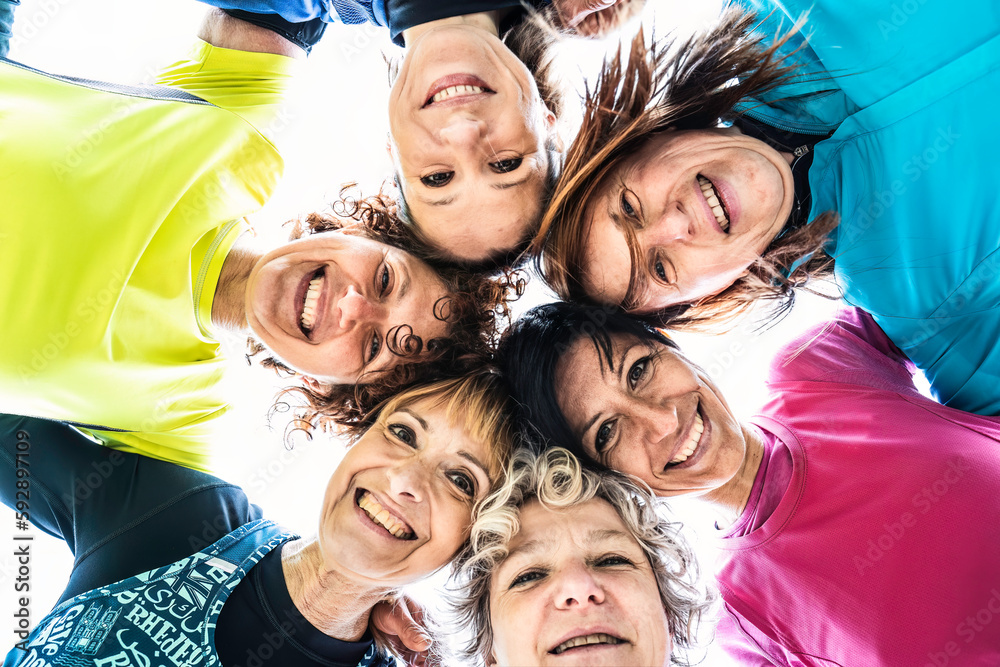 Multigenerational female friends embrace in a circle and looking down ...