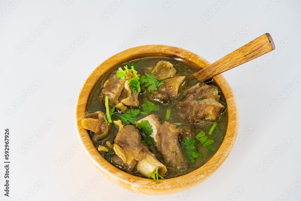 Fresh spicy lamb paya soup in a wooden bowl and ready to eat. Home made ...