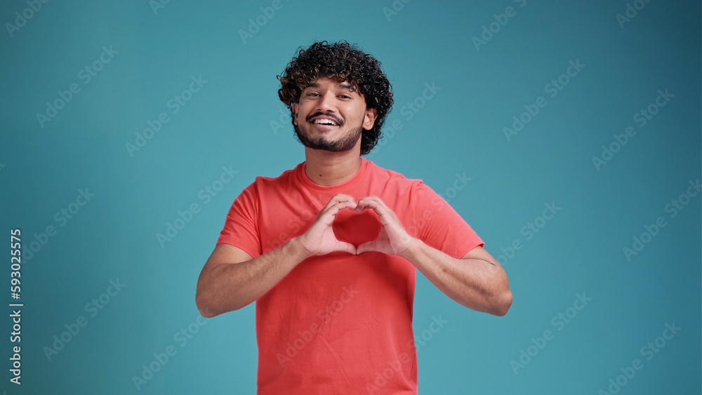 Handsome curly millennial hindu guy wearing coral t-shirt showing heart ...