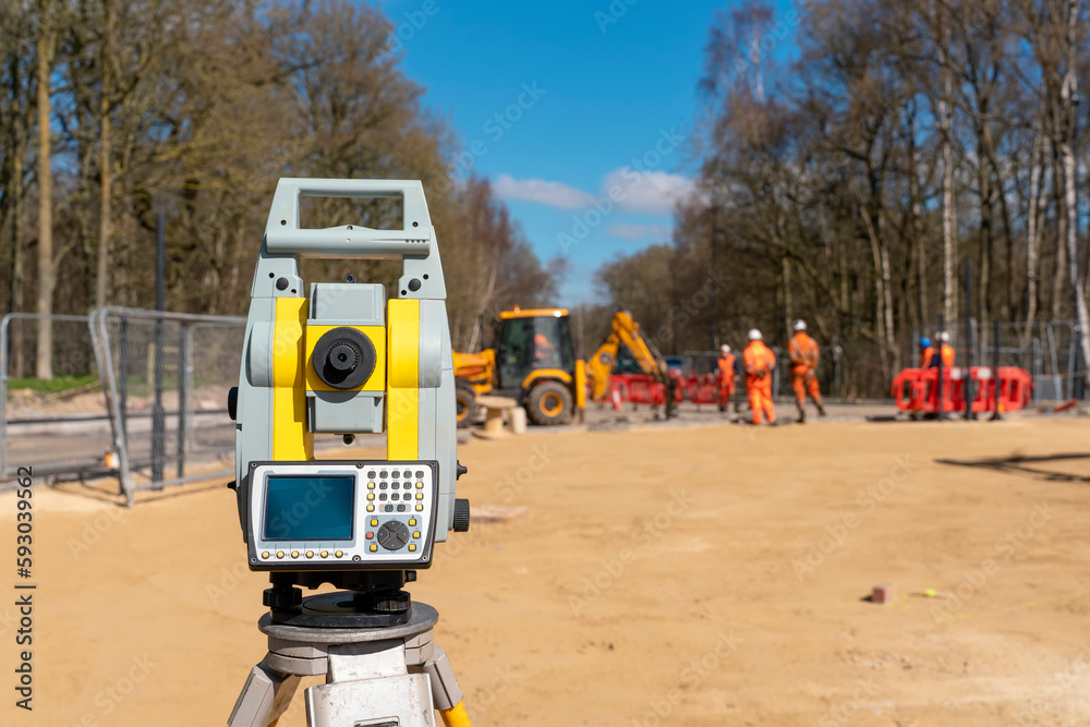 Yellow equipment set out on tripod on building site against cloudless ...