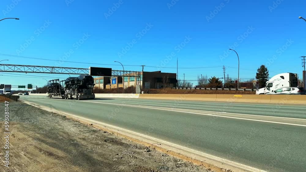 Truck with passenger cars in semi-trailer drives along the freeway exit ...