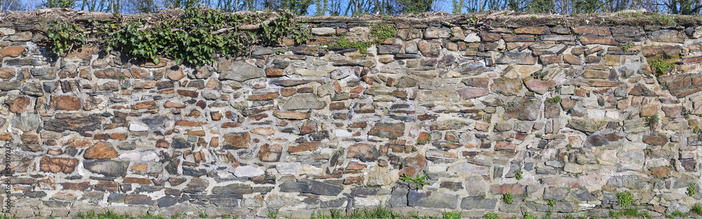 Rustic rough natural stone wall in panorama format. Can be seamlessly ...