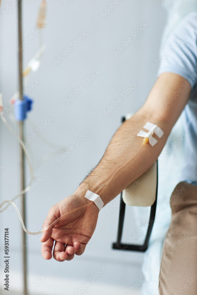 Vertical closeup of male hand with IV drip infusion in treatment ...