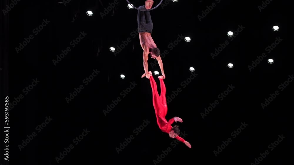 Circus aerial hoop duo with on black stage background performing trick ...