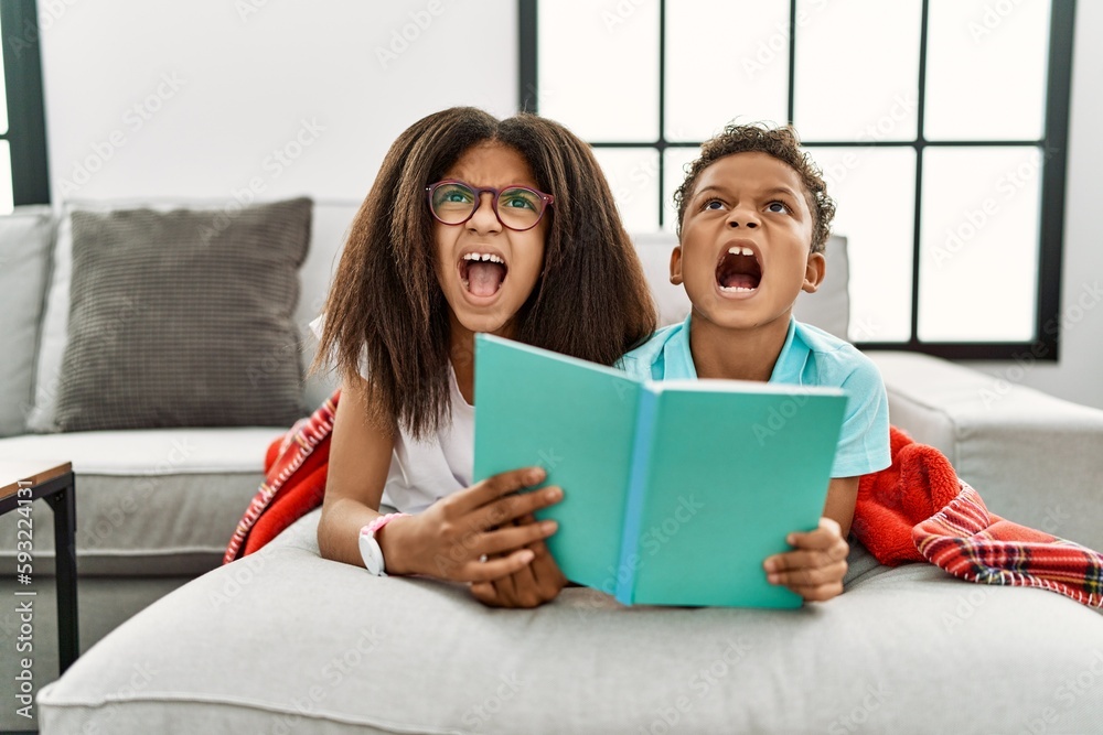Two siblings lying on the sofa reading a book angry and mad screaming ...